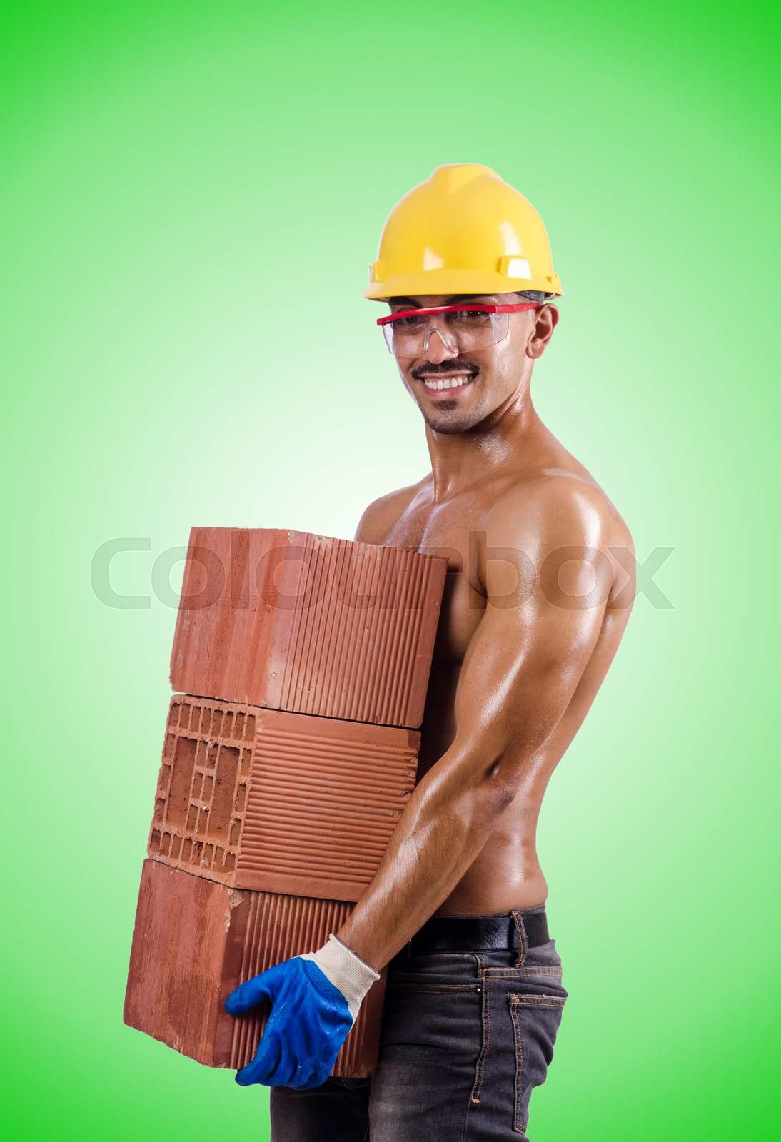Muscular builder with bricks against gradient | Stock image | Colourbox