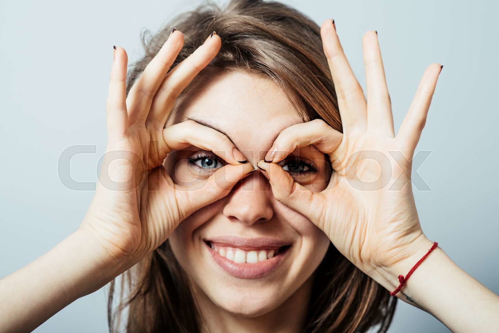 Young happy woman holding her hands over her eyes as glasses and ...
