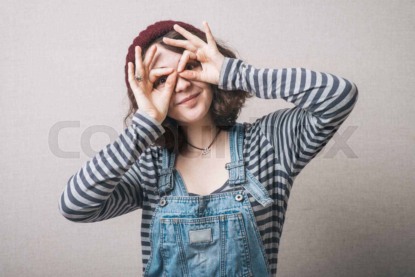 Young happy woman holding her hands over her eyes as glasses and ...
