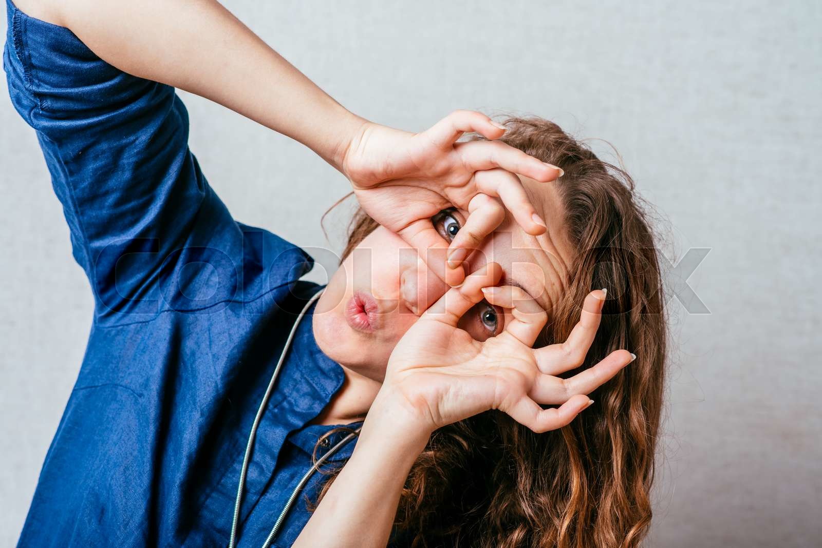 Young happy woman holding her hand over her eye as glasses and looking ...