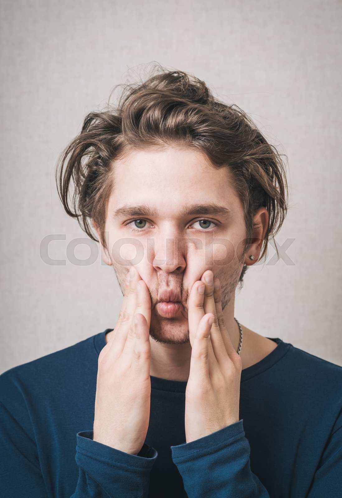 Young man squeezing her cheeks with her hands | Stock image | Colourbox