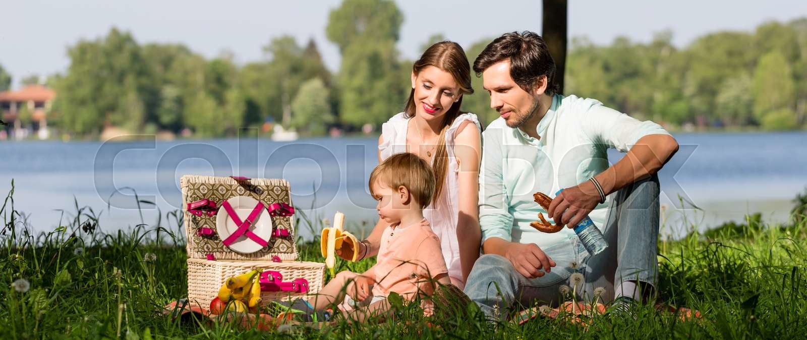 Family having picnic at lake sitting on meadow | Stock image | Colourbox