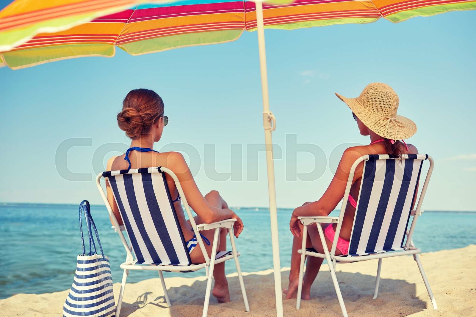 happy women sunbathing in lounges on beach | Stock image | Colourbox