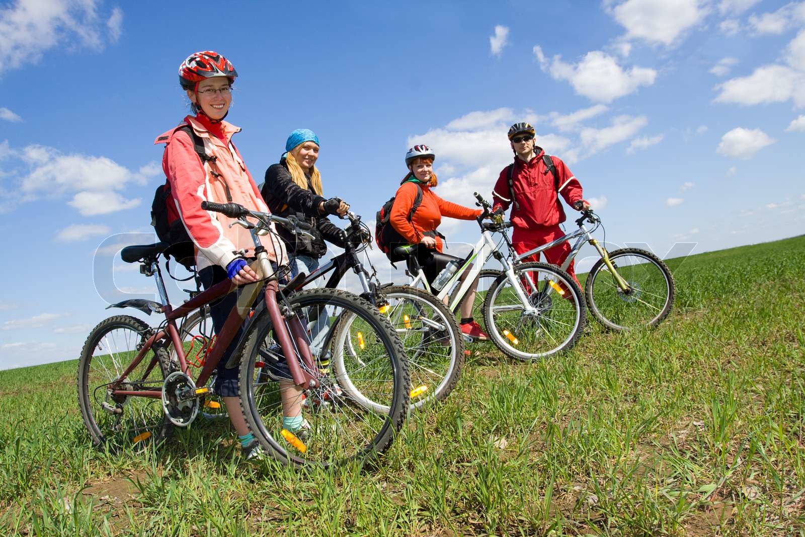 A group of four adults on bicycles in the countryside. Everyone can ...