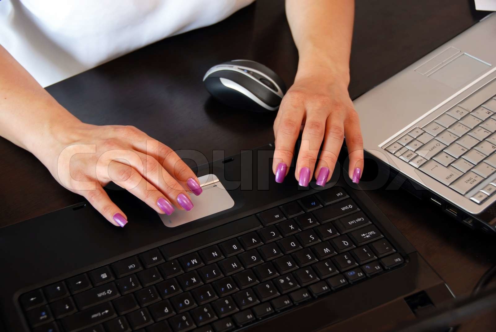 female hands purple nail polish on black notebook computer keyboard ...