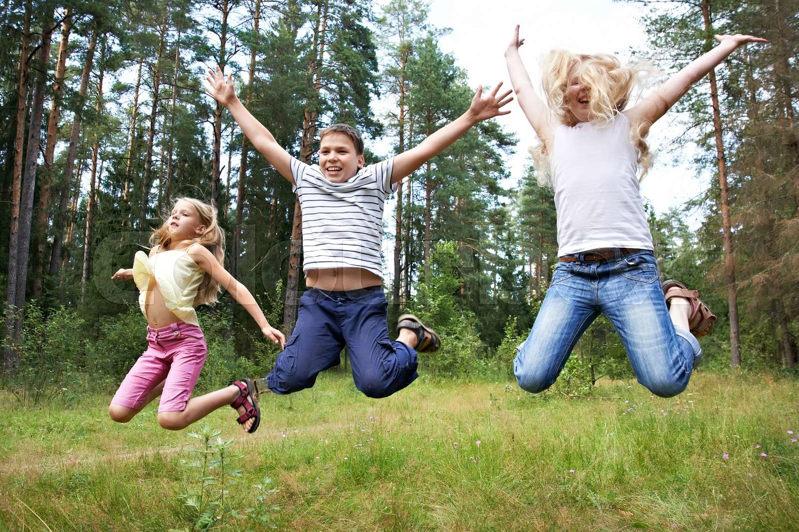 Children jump on lawn in summer forest | Stock image | Colourbox