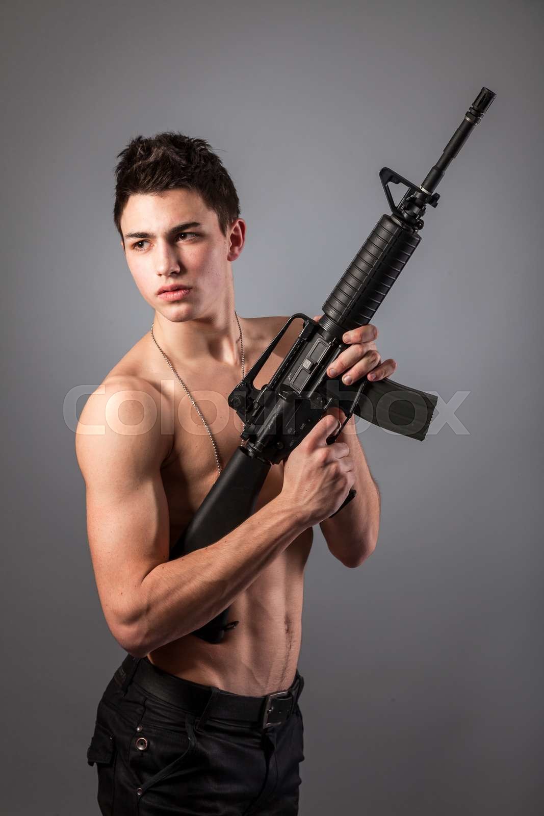 Handsome bare-chested soldier is holding a rifle | Stock image | Colourbox