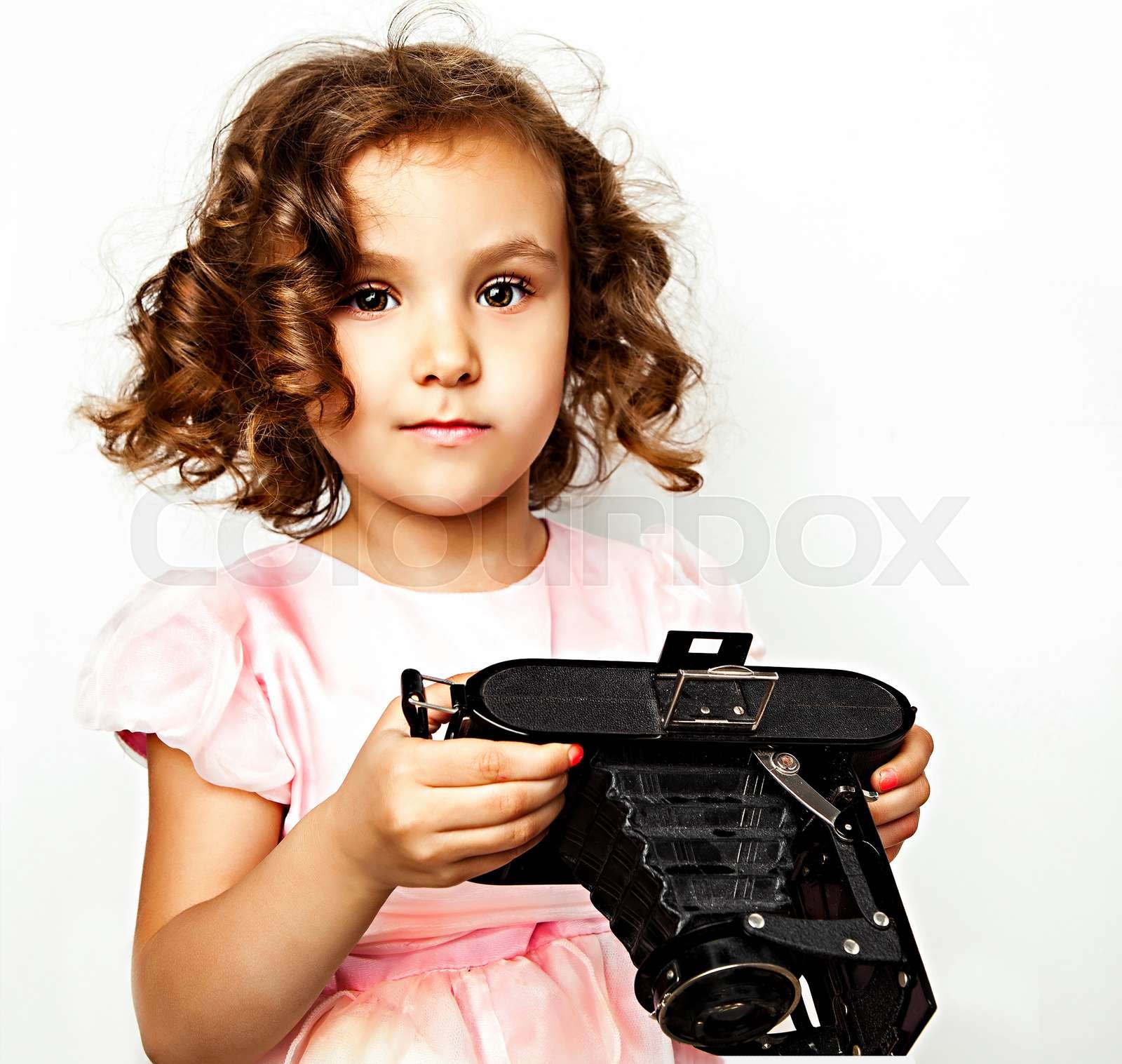 Close up portrait of beautiful little girl in pink dress posing with ...