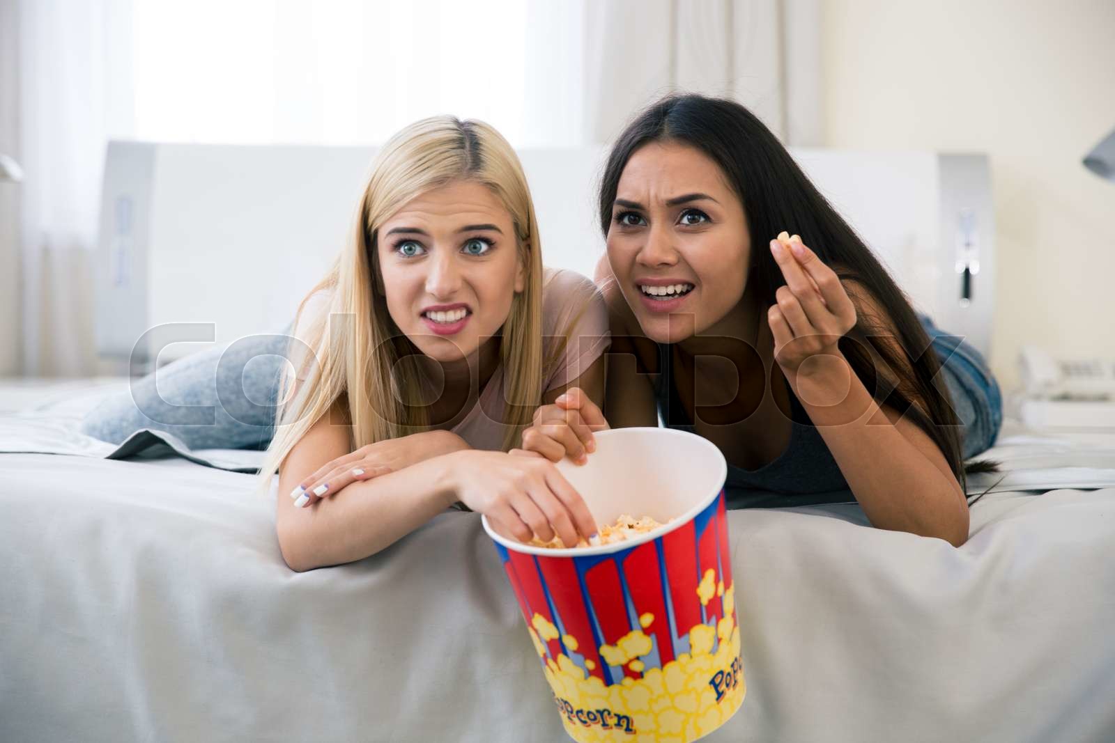 Two scared girls watching film | Stock image | Colourbox