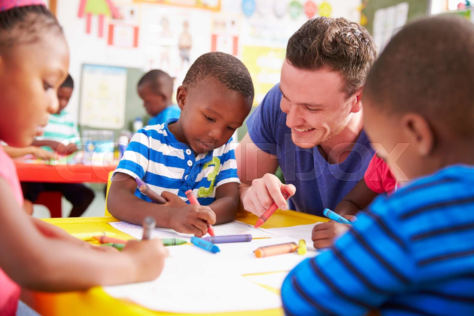 Volunteer teacher helping a class of preschool kids drawing | Stock ...