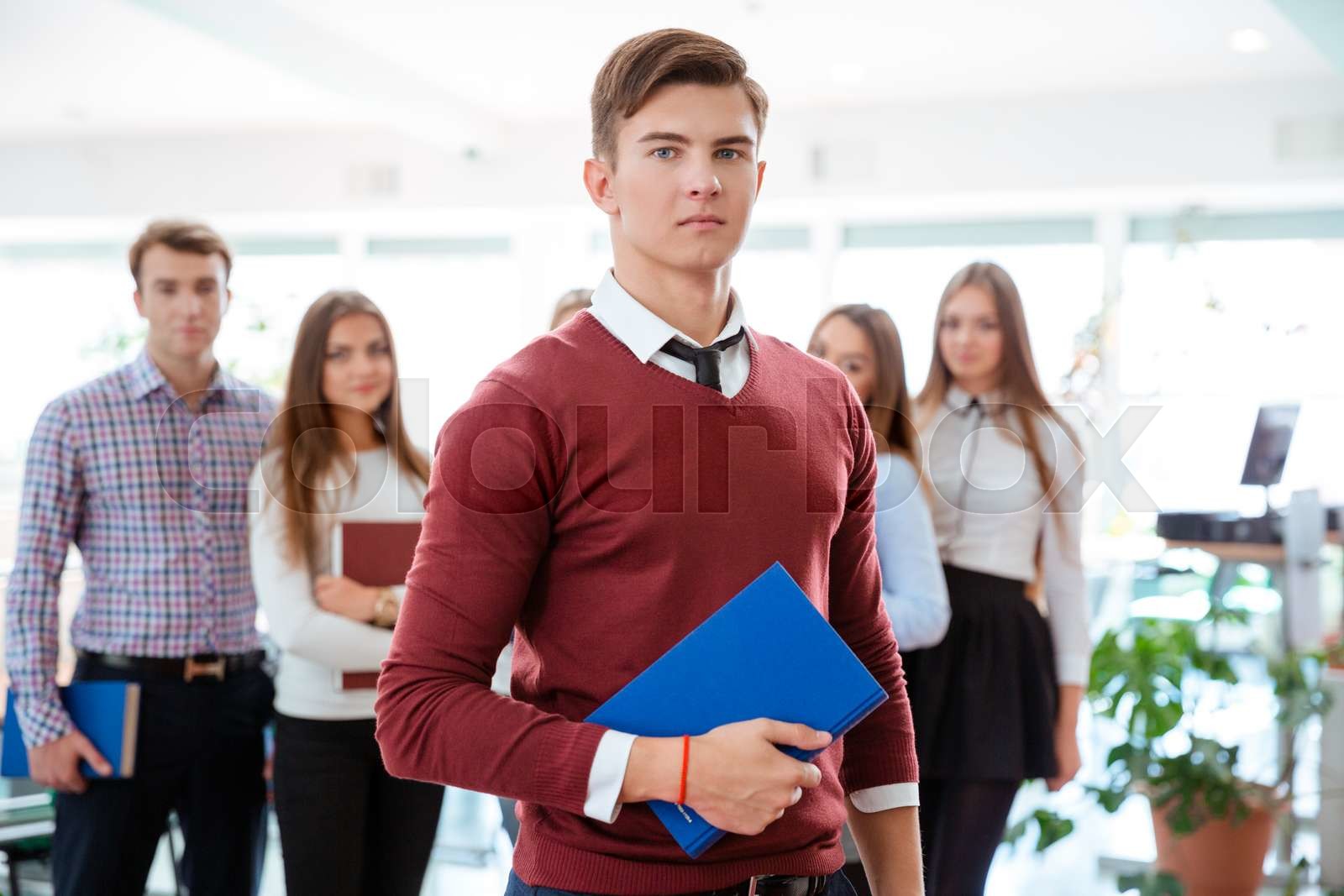 Handsome male student standing in classroom | Stock image | Colourbox
