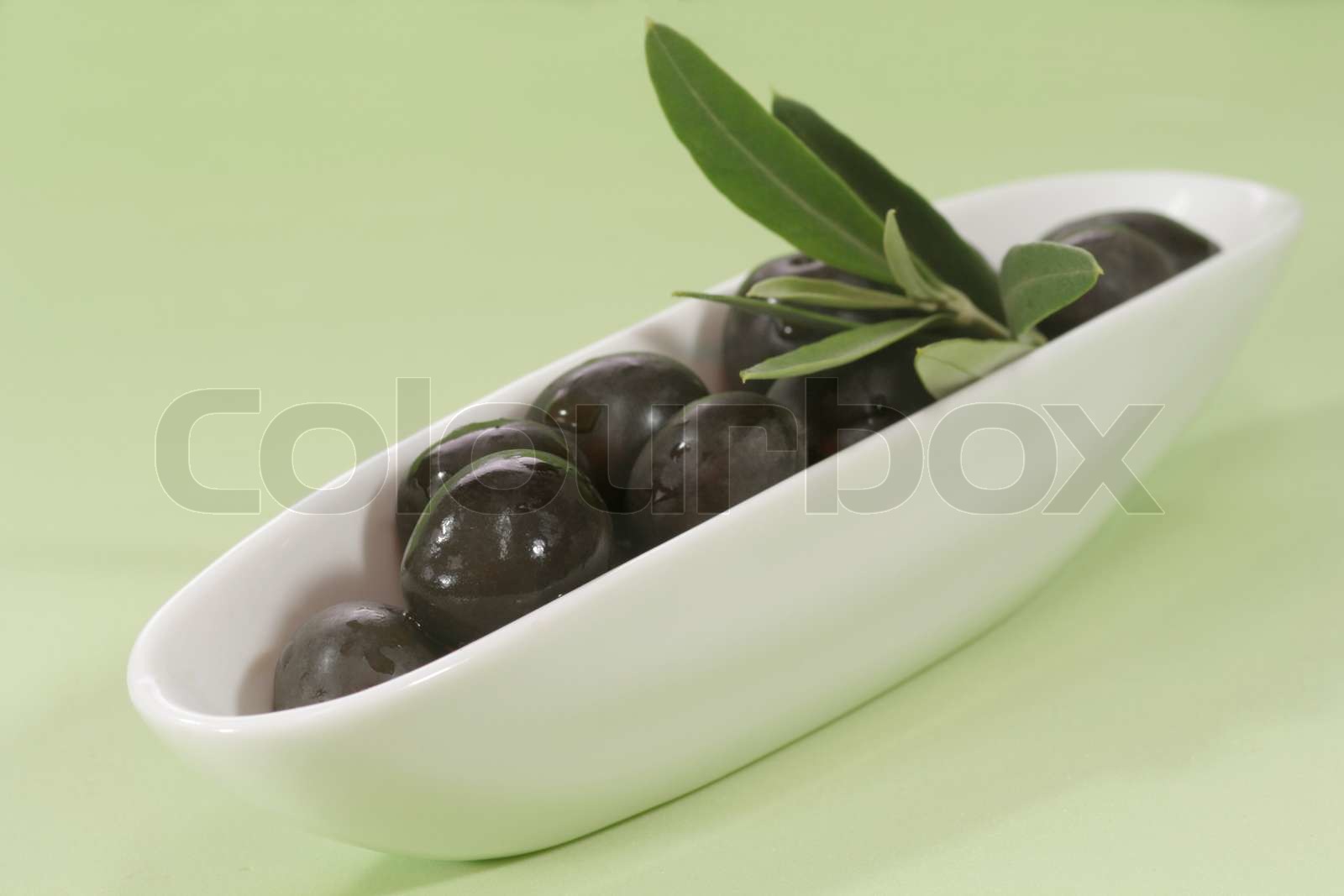 Sorte oliven med olivengren i en skål | Stock foto | Colourbox