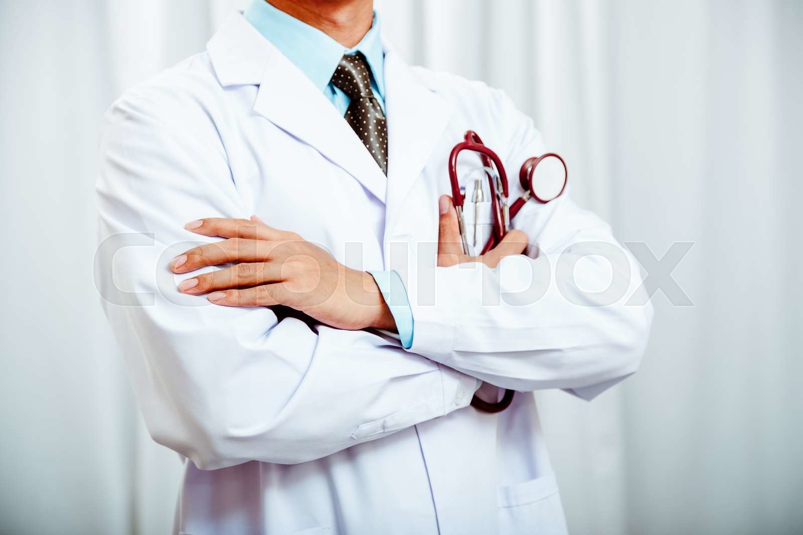 doctor folding arms holding stethoscope | Stock image | Colourbox