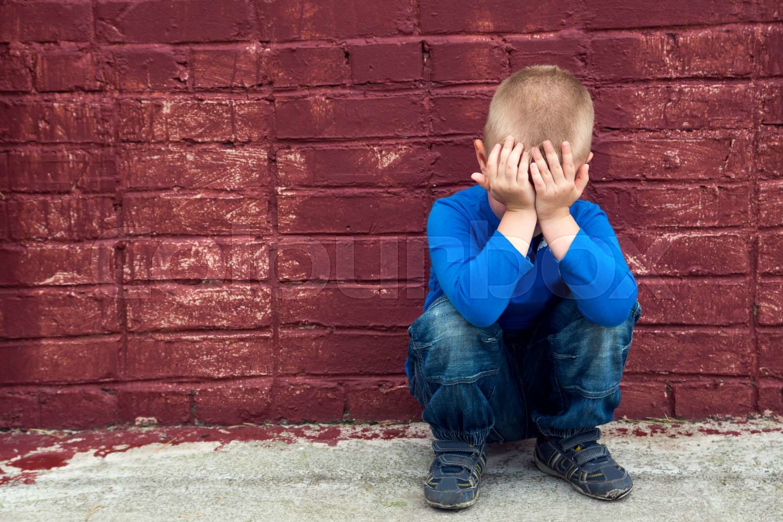 poor crying child near brick wall | Stock image | Colourbox