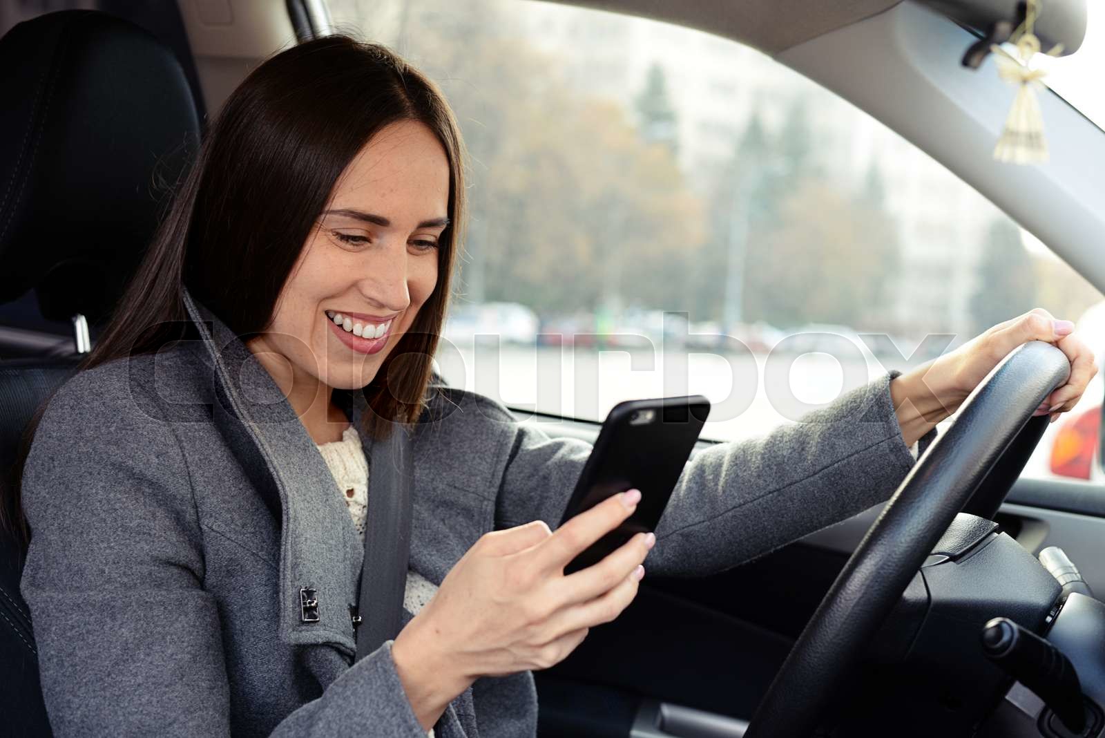 woman driving the car and chatting on smartphone | Stock image | Colourbox