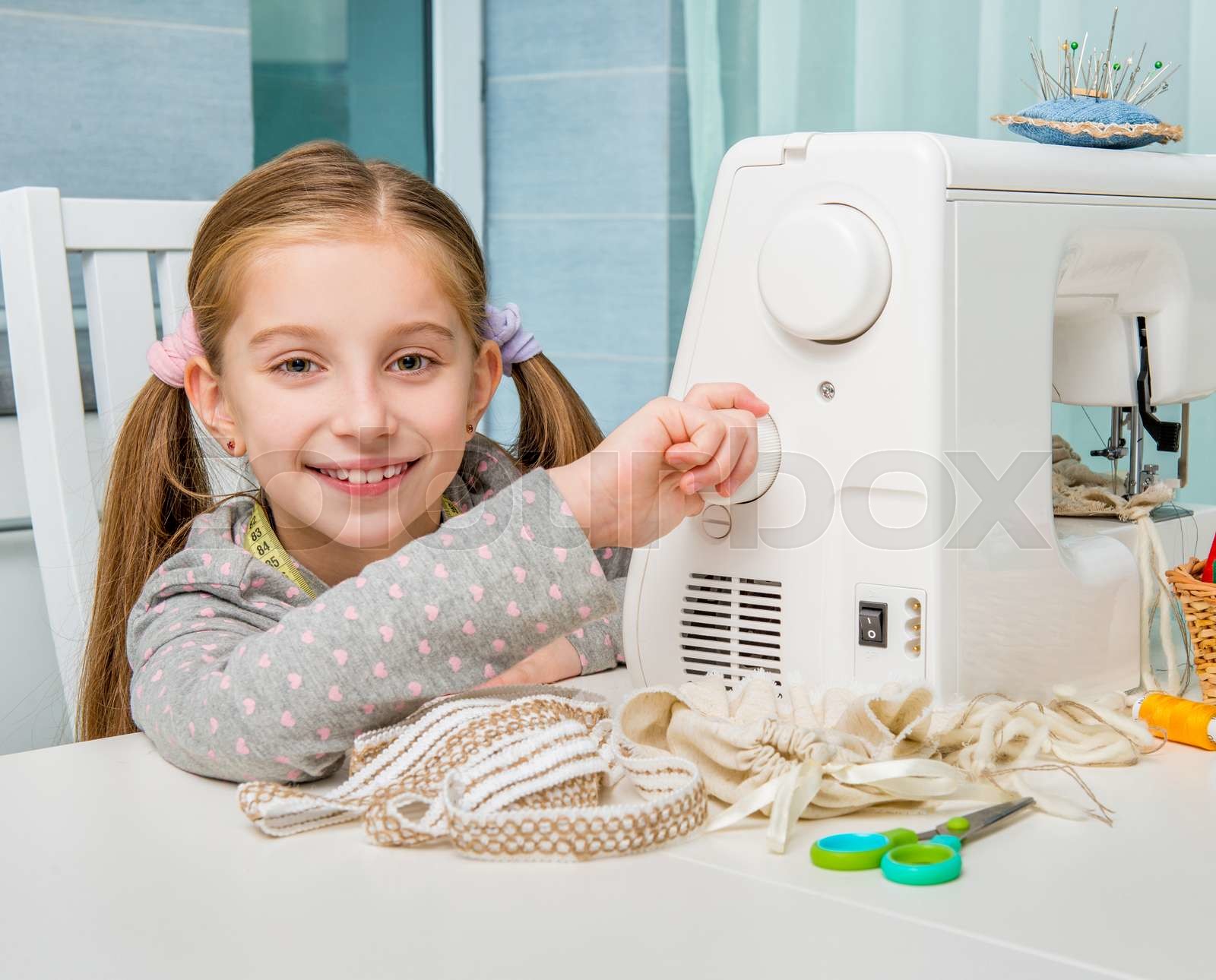 smiling little girl at the table with sewing machine | Stock image ...