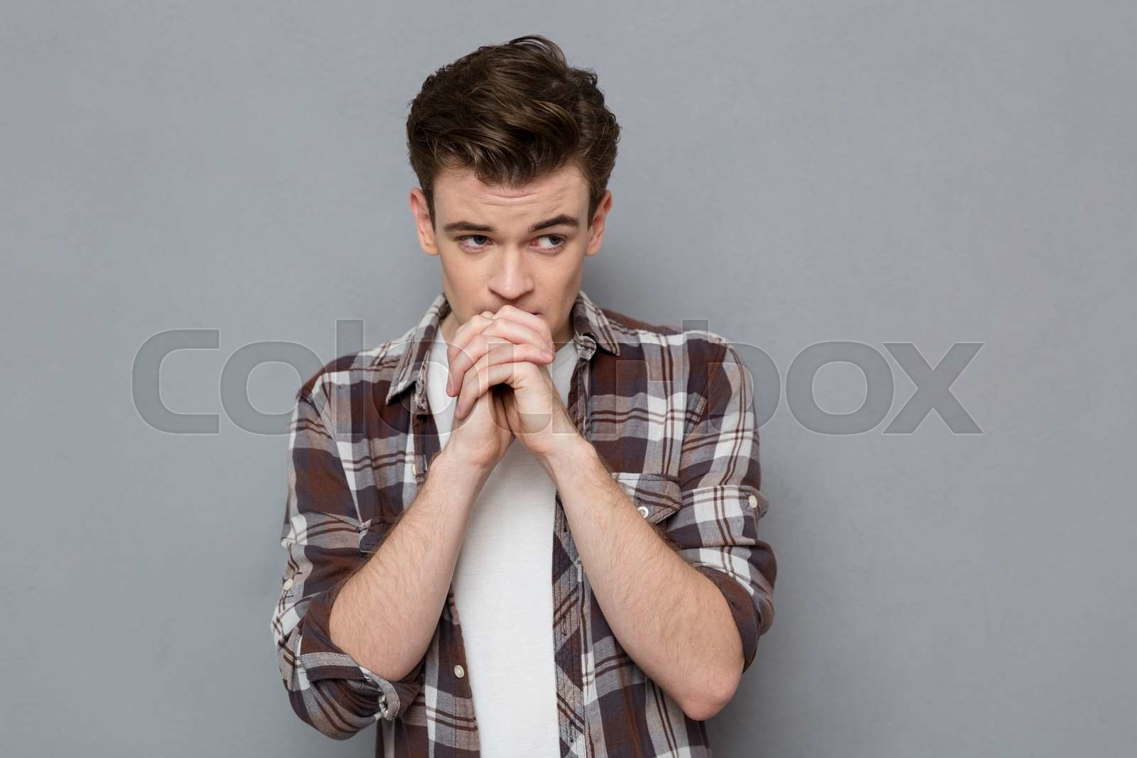 Scared young handsome guy waiting and praying | Stock image | Colourbox