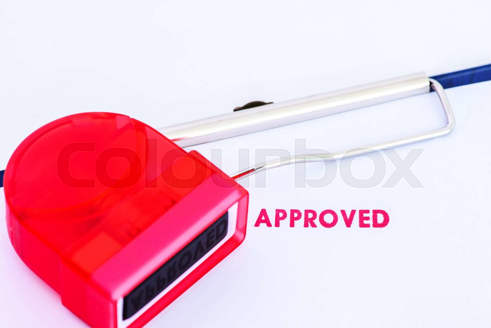 Red approved stamp on white paper with rubber stamper and clipbo ...