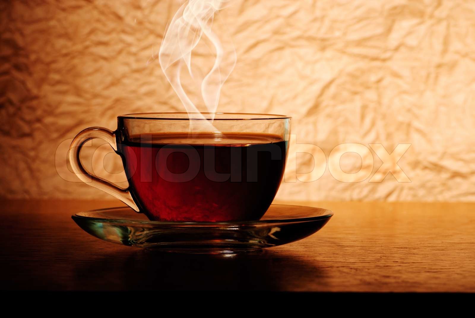 Glass cup of black tea on wooden table with smoke | Stock image | Colourbox
