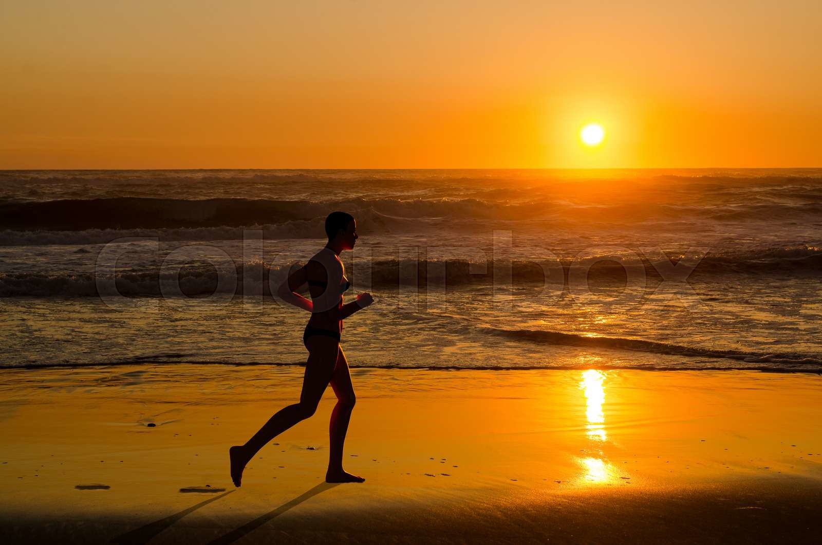 Woman jogger running on sunset beach | Stock image | Colourbox