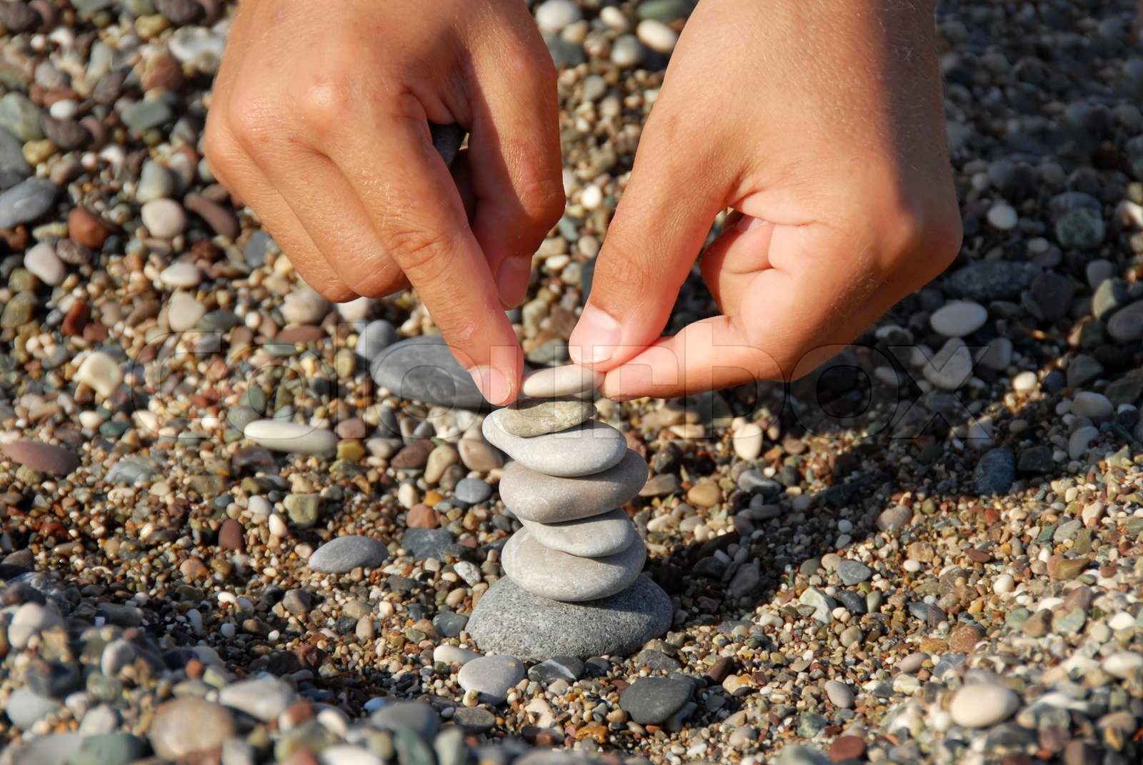 child hands building a rocks stack carefully | Stock image | Colourbox