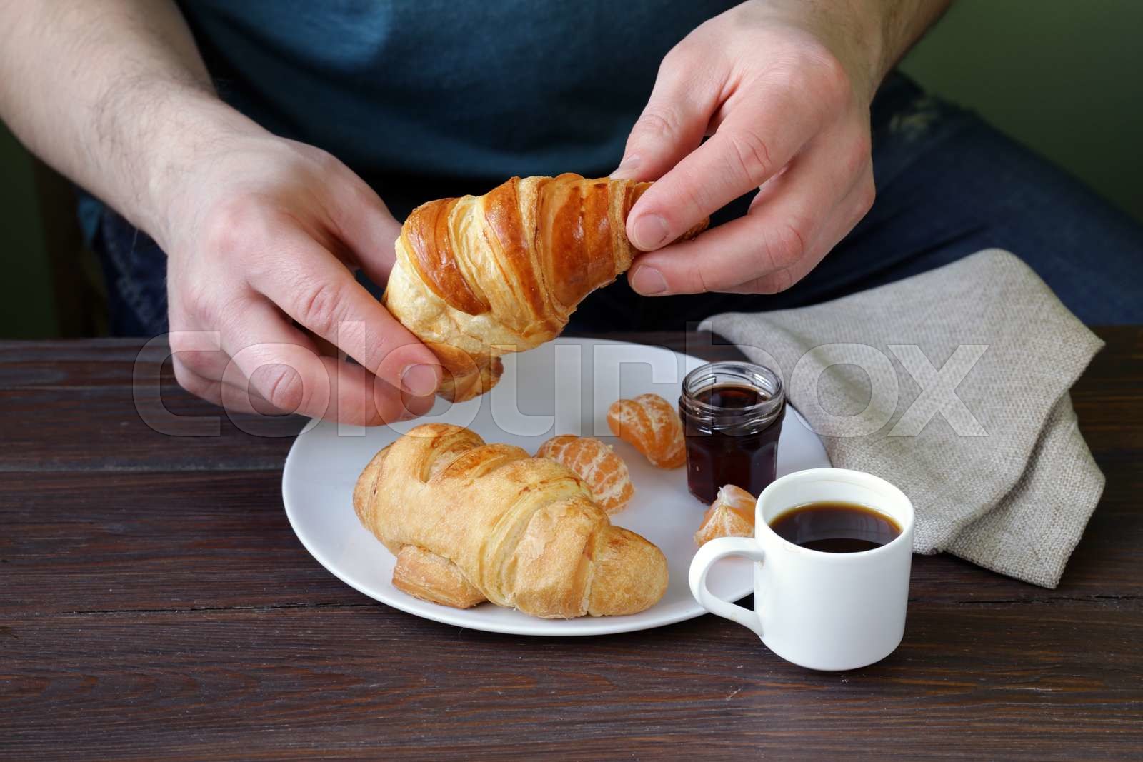 man eating a croissant with jam for breakfast | Stock image | Colourbox