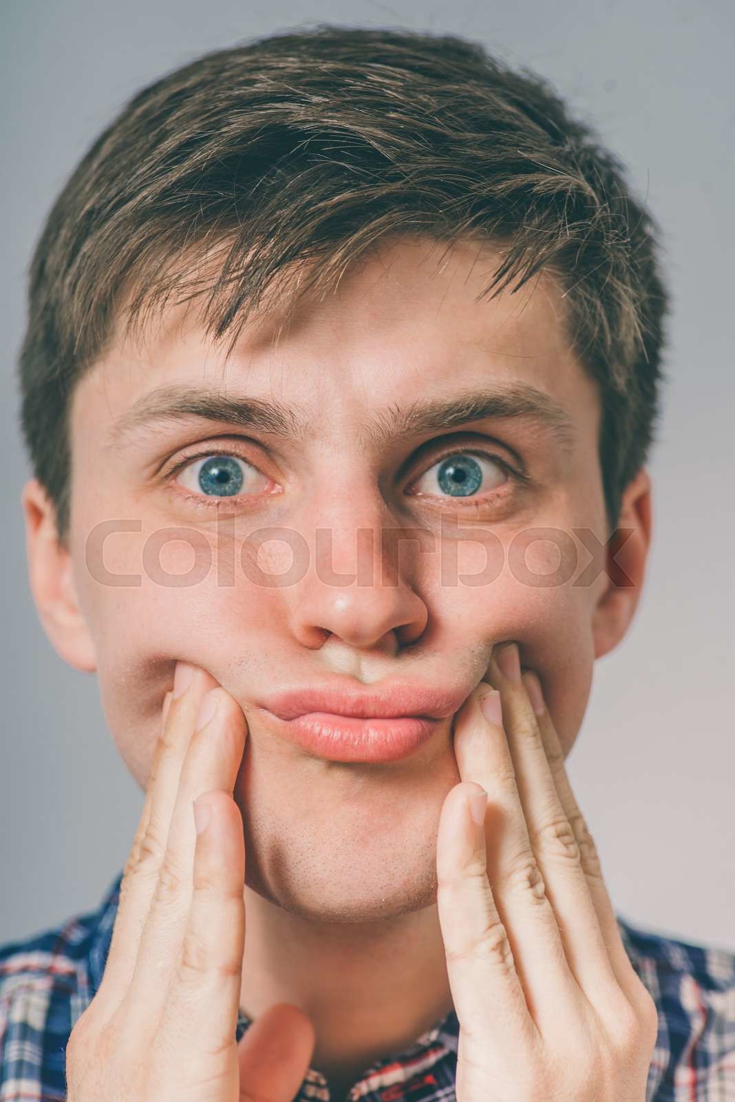 Young man squeezing her cheeks with her hands | Stock image | Colourbox