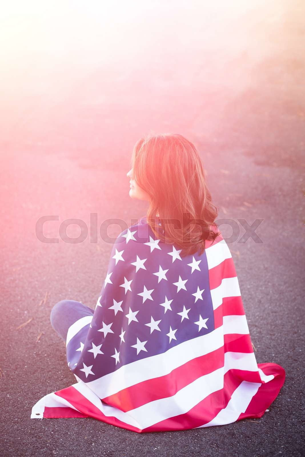 Dreaming patriot woman sitting down with american flag wrapped around ...