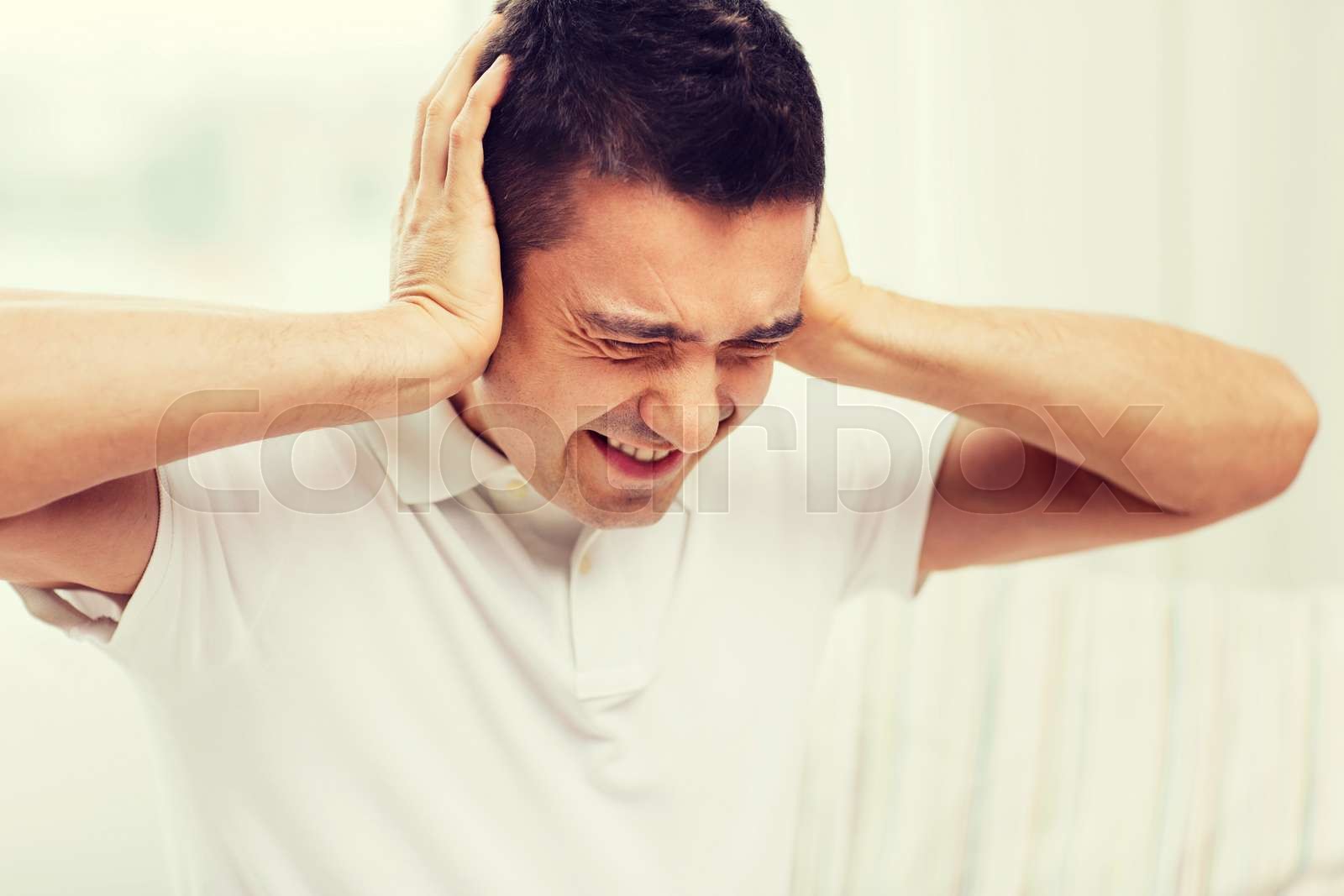 unhappy man closing his ears by hands at home | Stock image | Colourbox