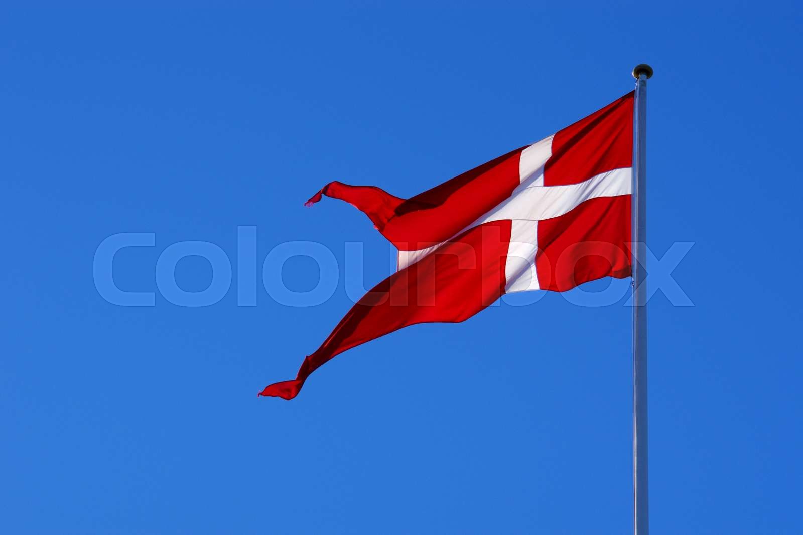 Dansk flag, Dannebrog, på flagstang med blå himmel | Stock foto | Colourbox