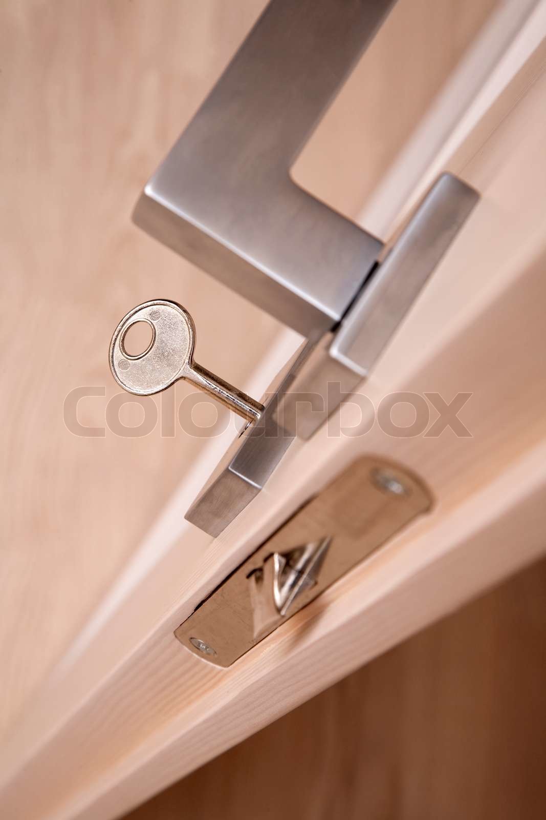 Metal door handle with a key in a keyhole | Stock image | Colourbox