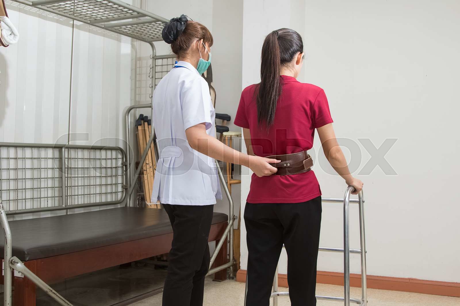 Physical therapist helping patient to walk using walker in hospital ...