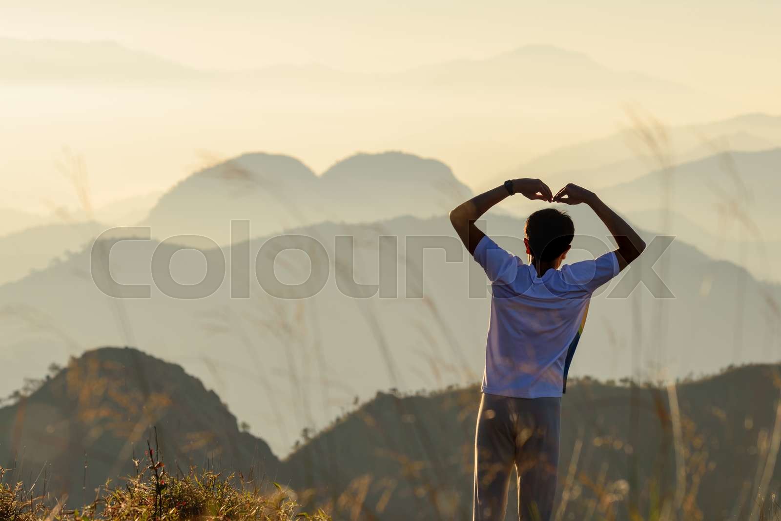 Backside of man is forming a heart shape at sunset with natural heart ...