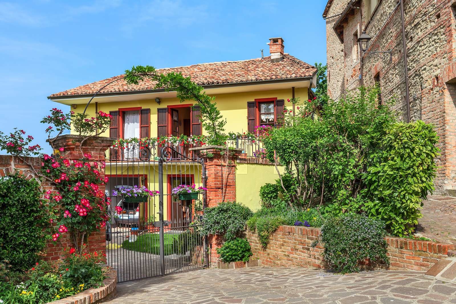Brick fence with metal gate in front of small yard and typical italian ...