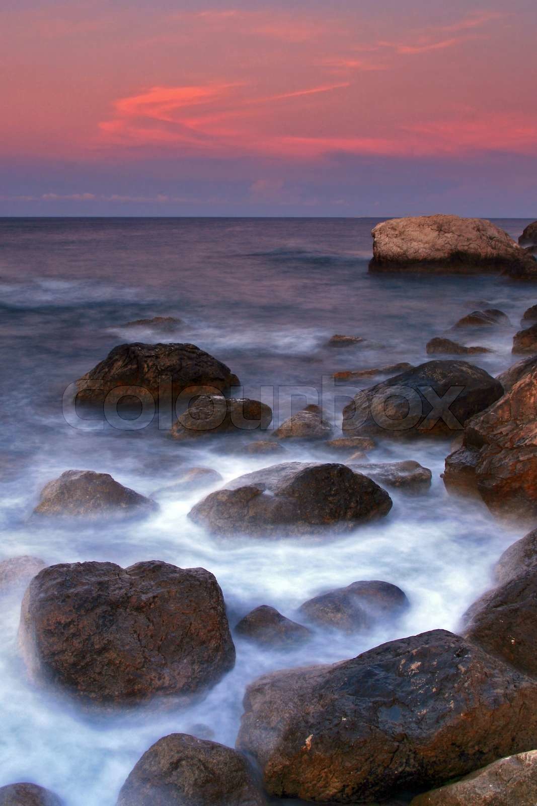 Waves crash on a rock in the sunset on the ocean coast | Stock image ...