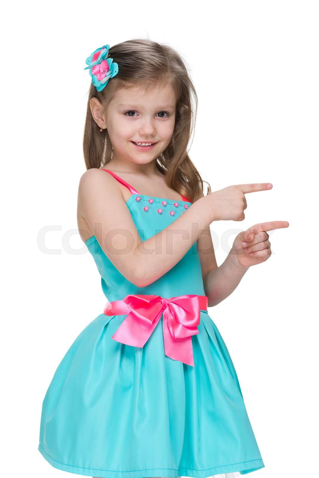 Smiling little girl shows her fingers to the side | Stock image | Colourbox