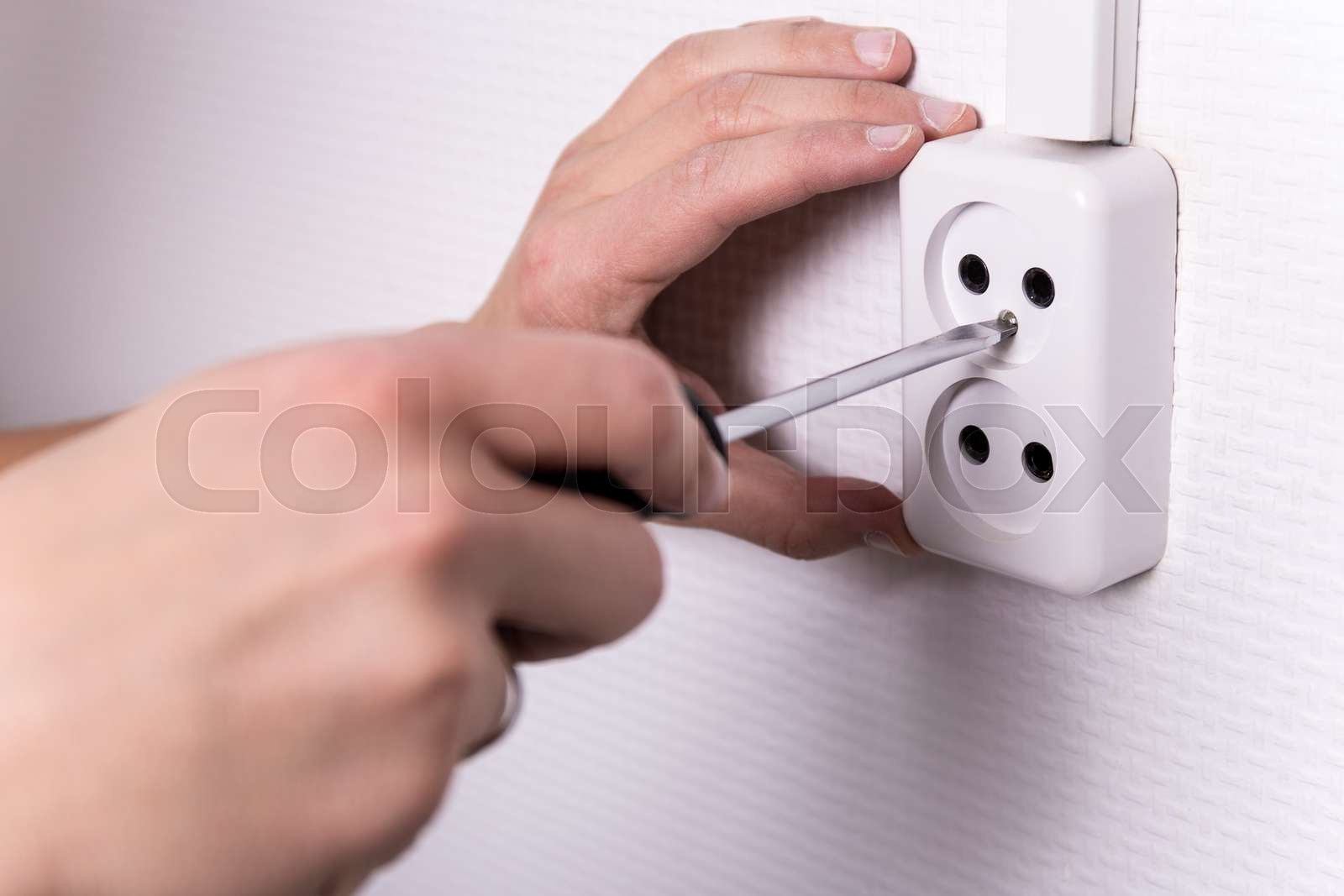 male hands with screwdriver installing electrical socket on wall ...
