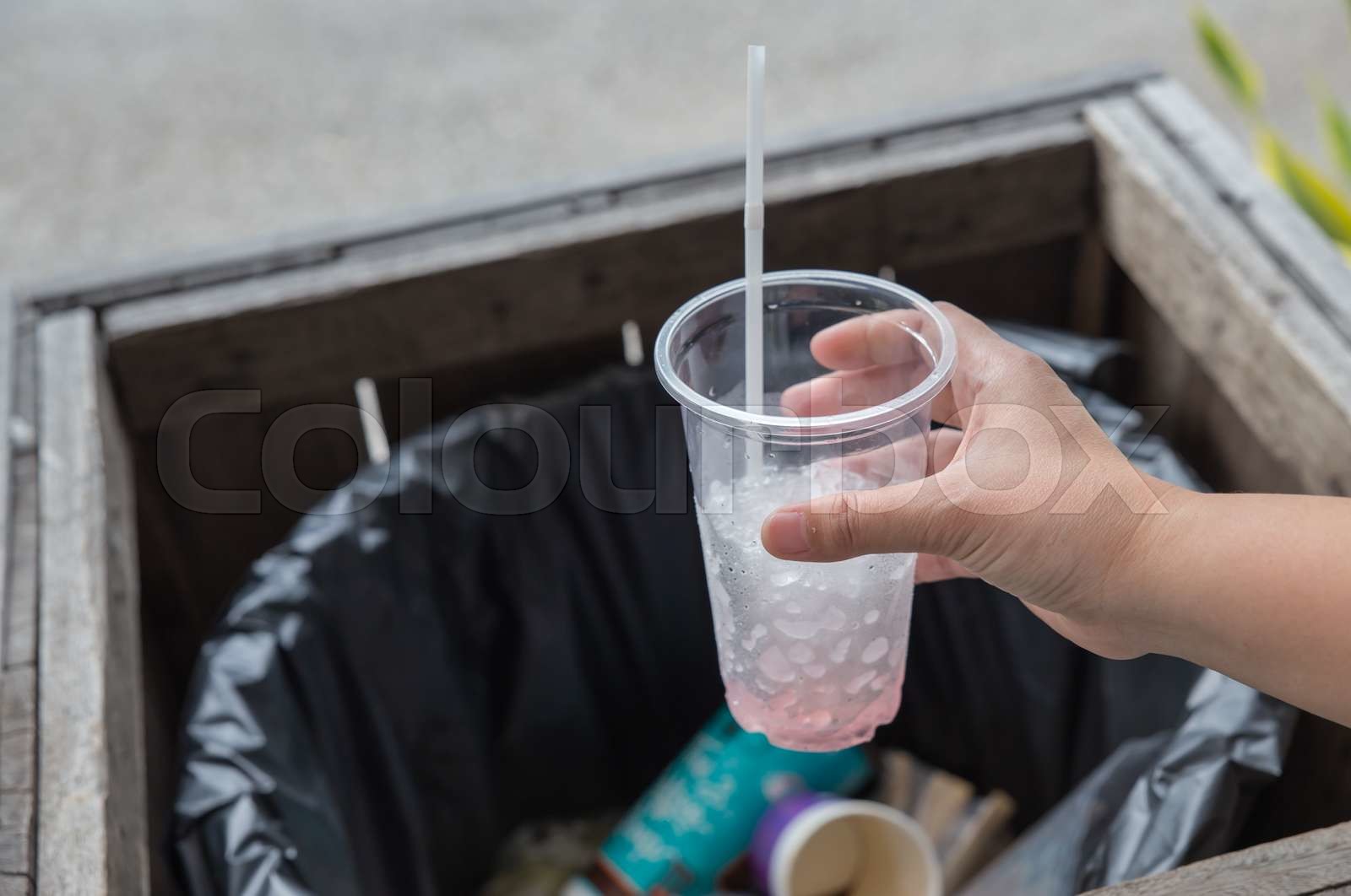 Closeup hand holding piece of garbage in trash can | Stock image ...