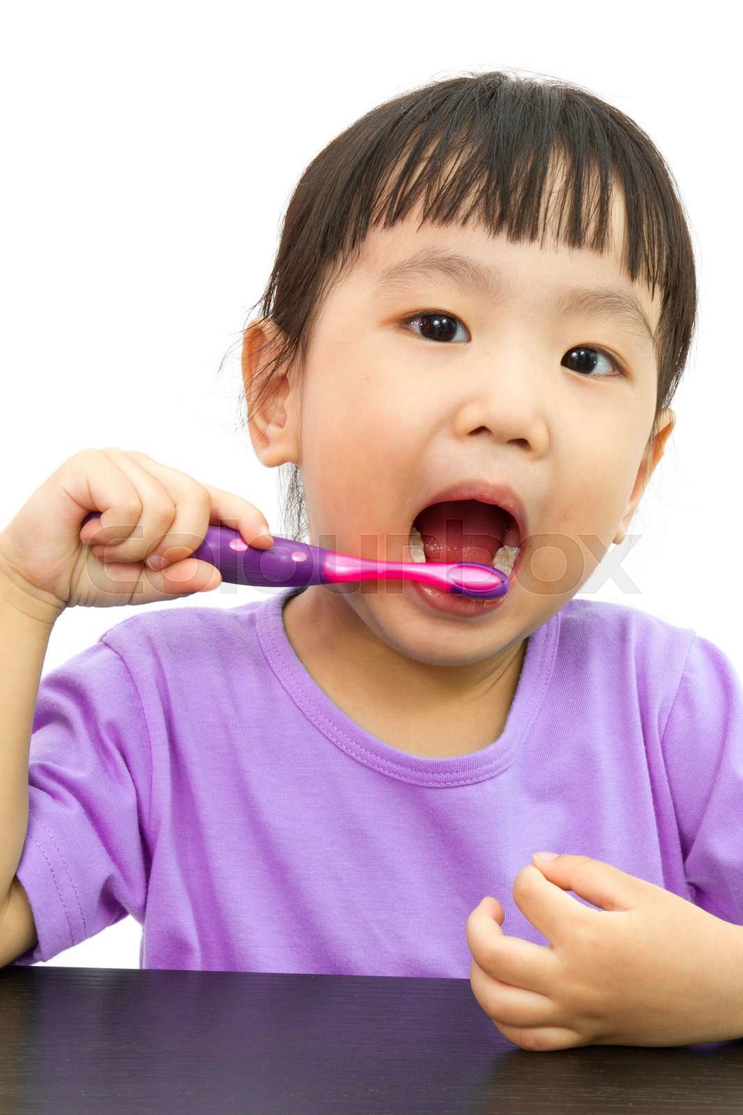 Chinese little girl brushing teeth | Stock image | Colourbox