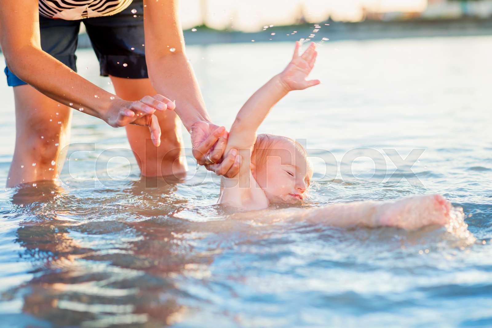 Little boy slipping accidentaly into water held by mother | Stock image ...