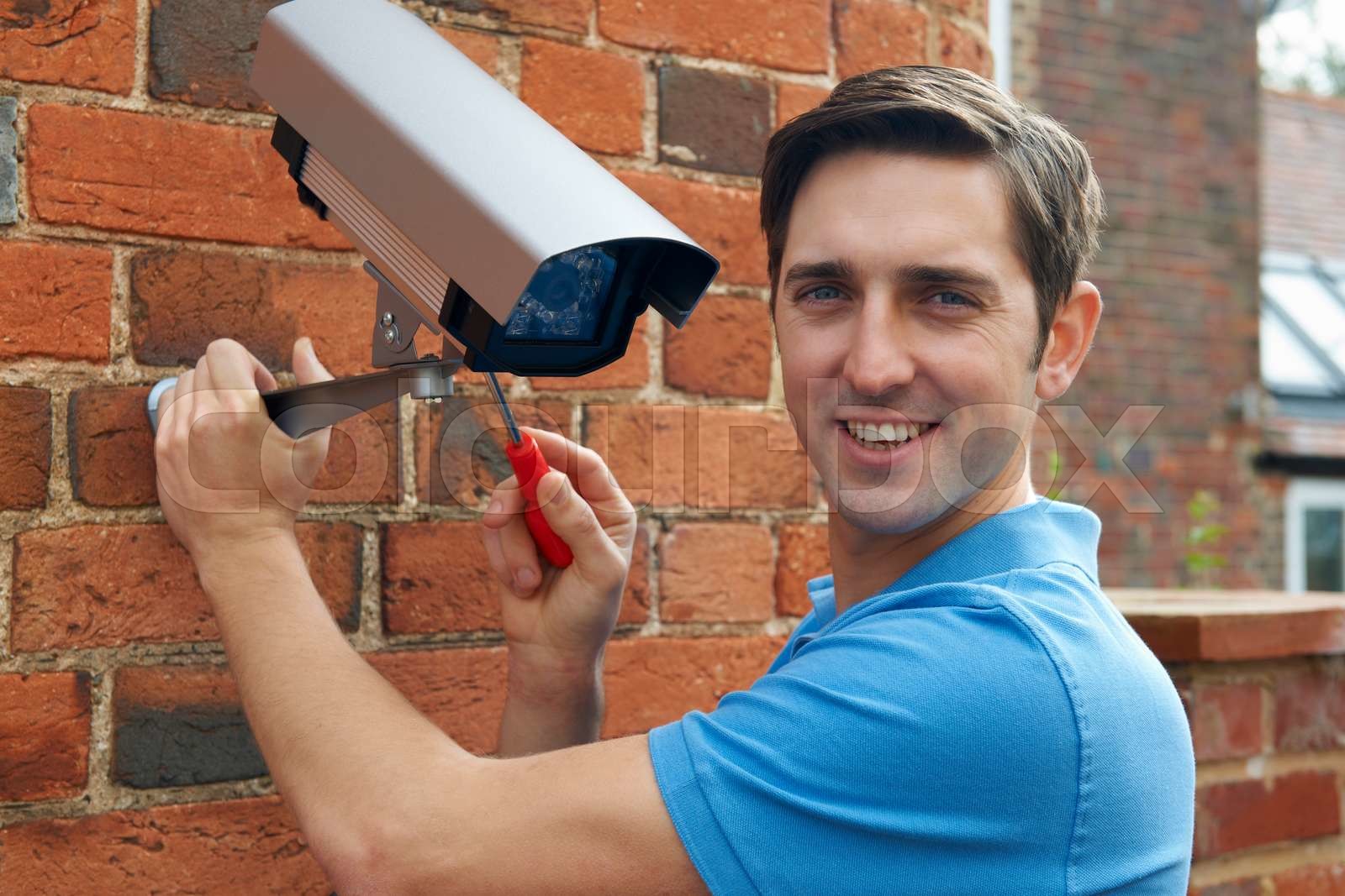 Man Fitting Security Camera To House Wall | Stock image | Colourbox