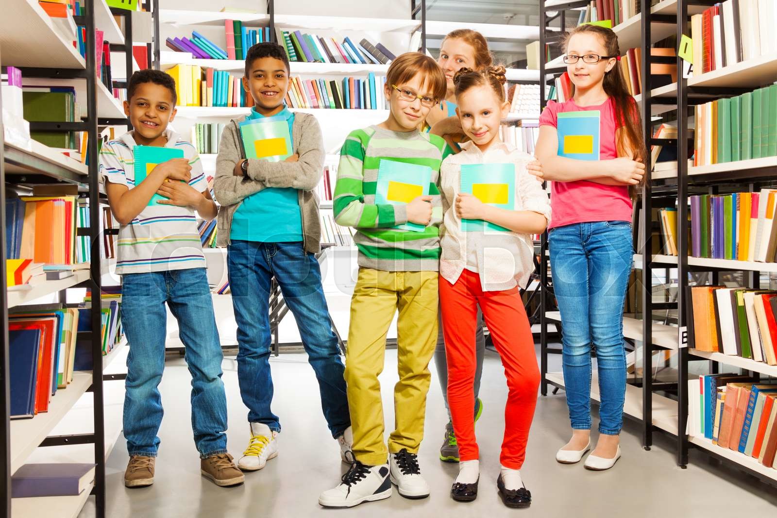 Children in library holding exercise books | Stock image | Colourbox