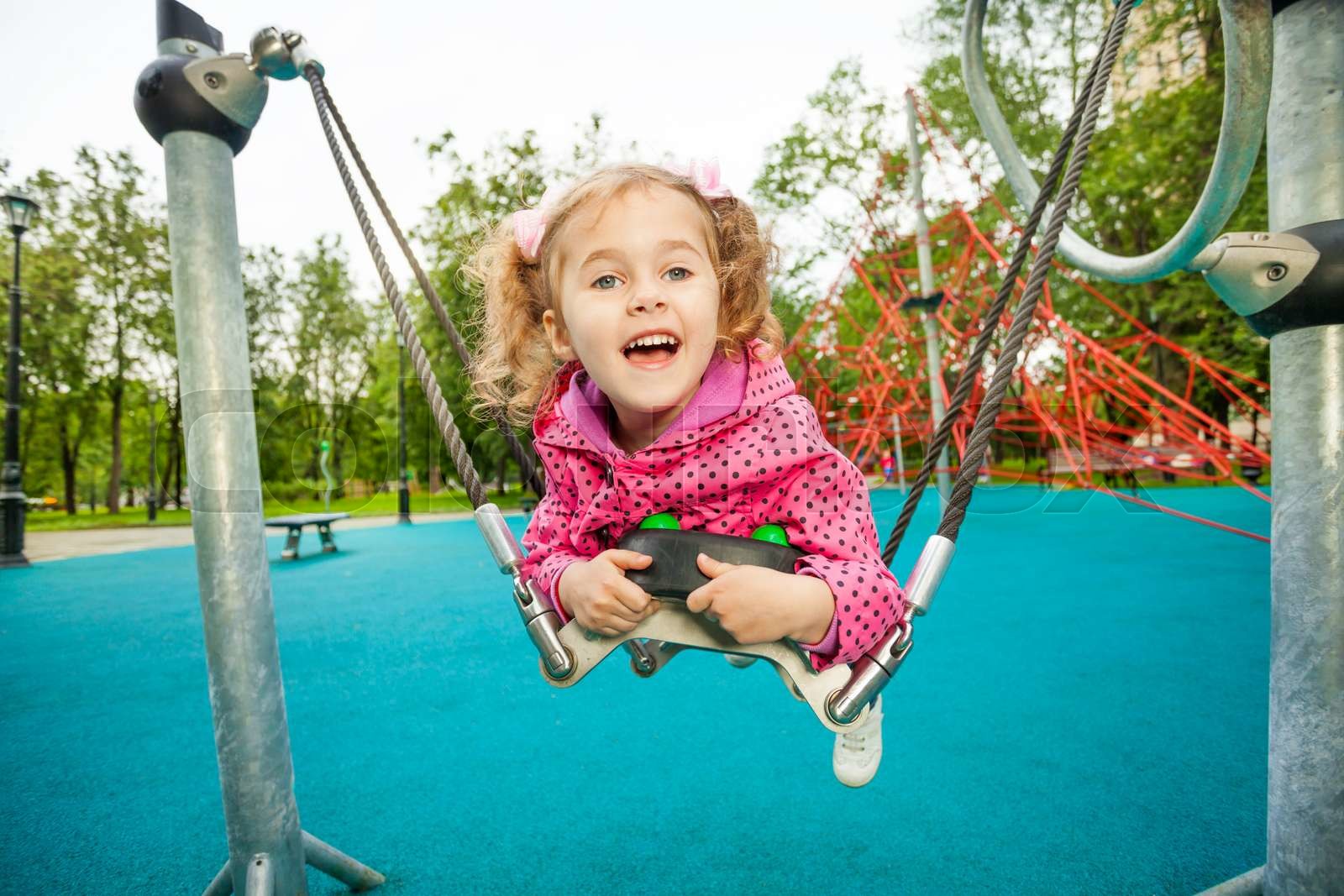 Laughing girl laying and swinging on swing set | Stock image | Colourbox