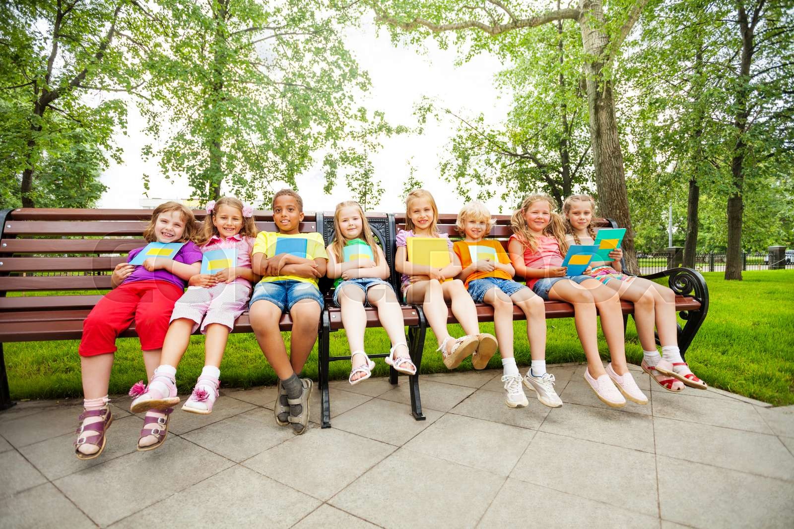 Children Sitting In A Row On Bench With Notebooks Stock Image Colourbox