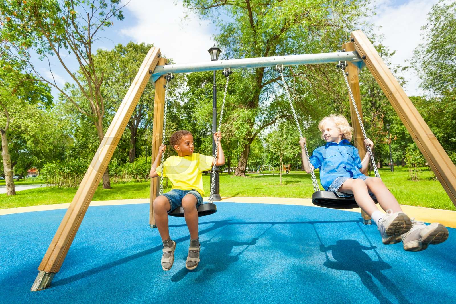 Kids on swings staring at each other and sit | Stock image | Colourbox