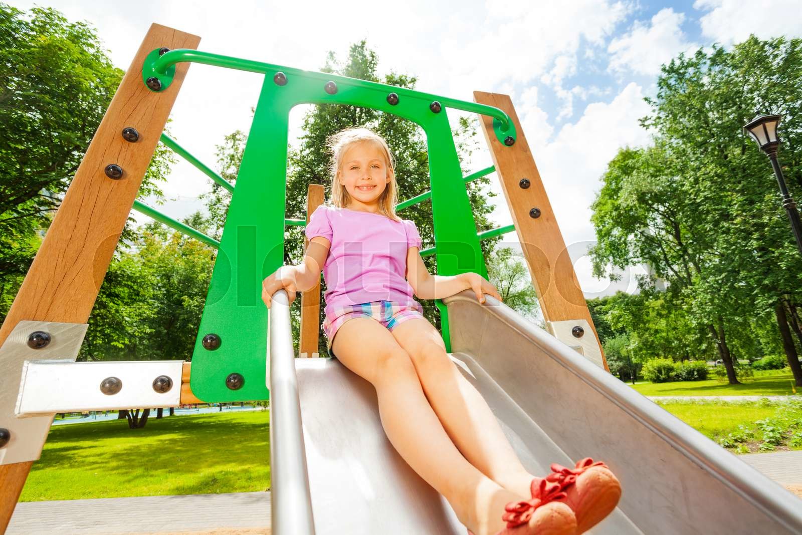 Charming girl on playground chute ready to slide | Stock image | Colourbox