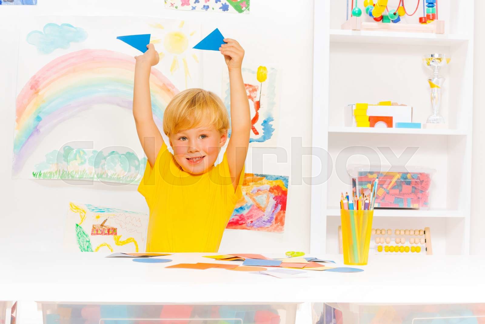 Blond cute boy learning shapes holding triangles | Stock image | Colourbox
