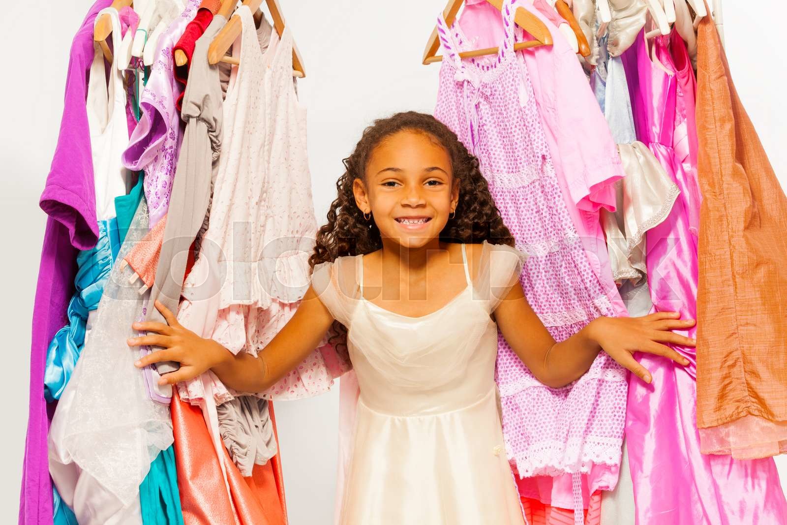 Small African girl standing between hangers | Stock image | Colourbox