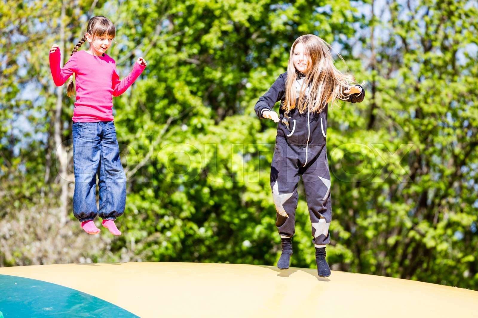 Smiling young girls jumping on bouncing pad | Stock image | Colourbox