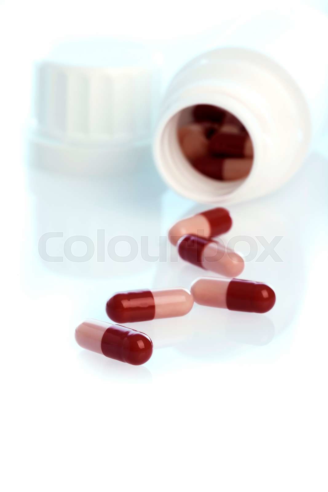 medicine capsules falling from tilted bottle | Stock image | Colourbox
